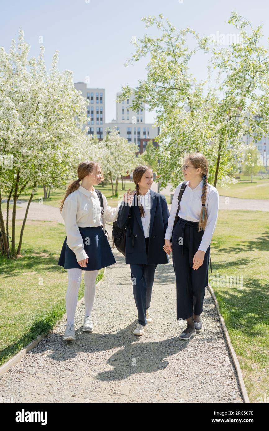 Smiling young teenage girls in uniforms looking at each other while ...