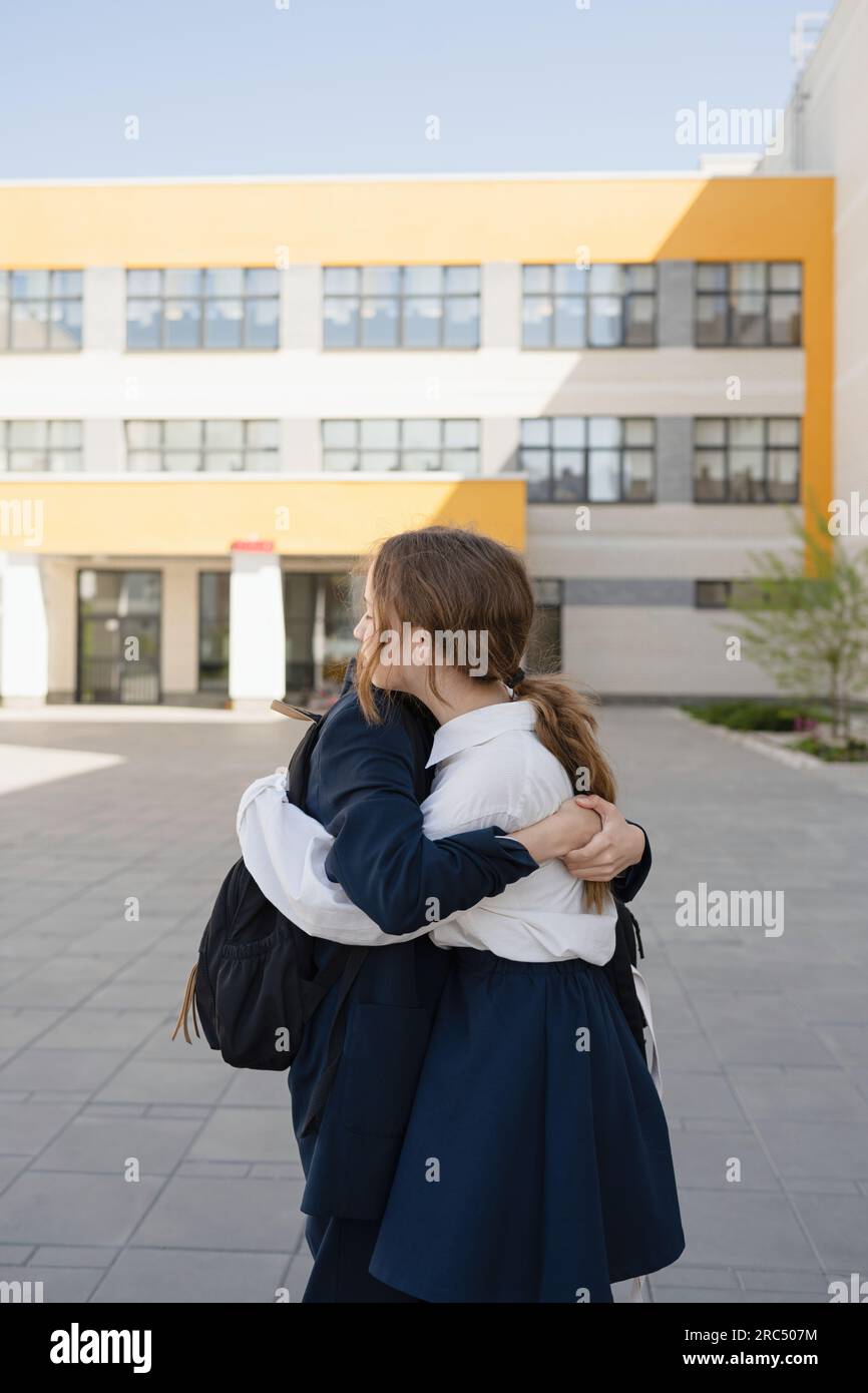 Young teenage girl student hugging anonymous classmate in uniform with ...