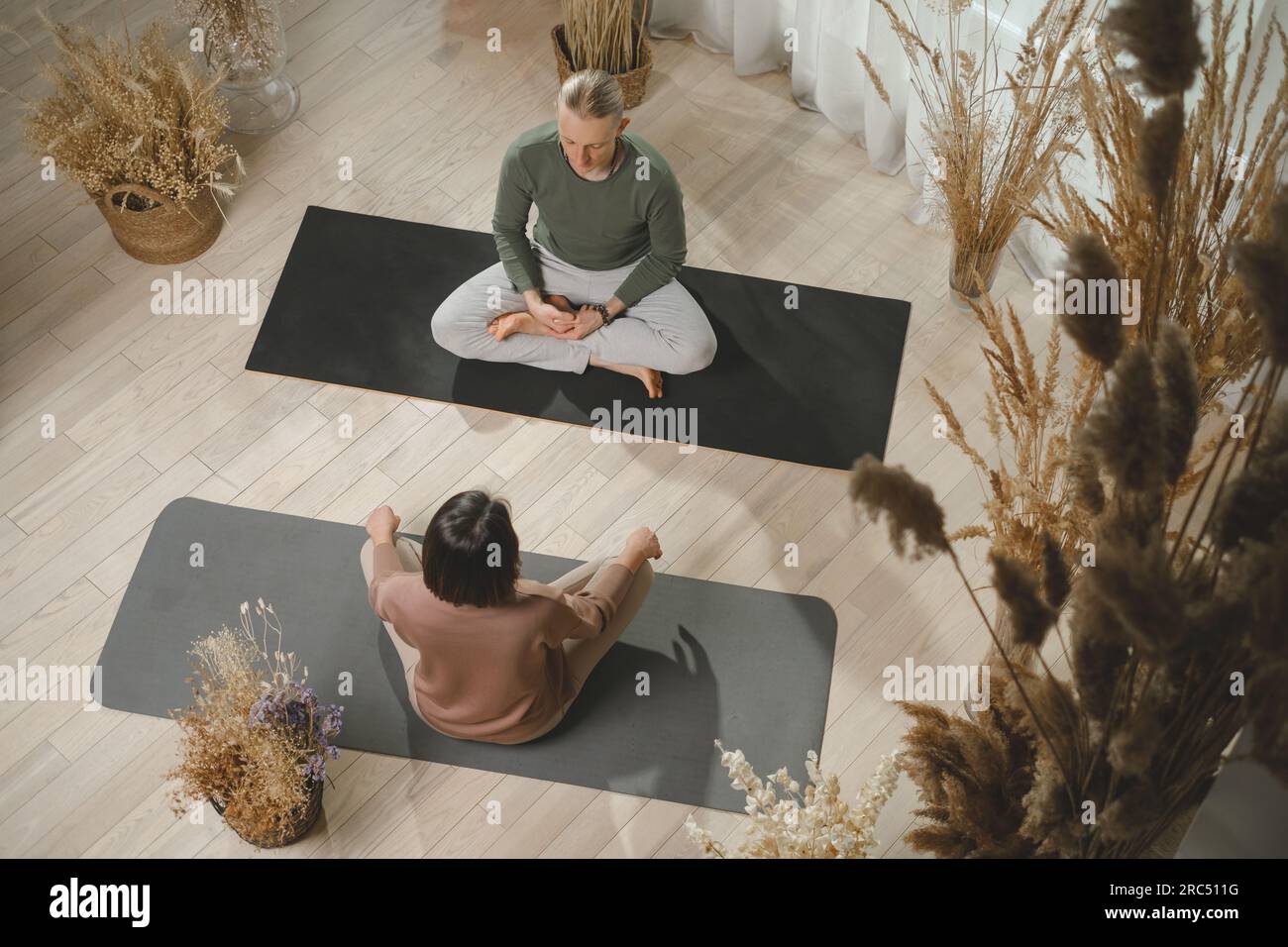 From above of husband and wife in sportswear meditating in Padmasana ...