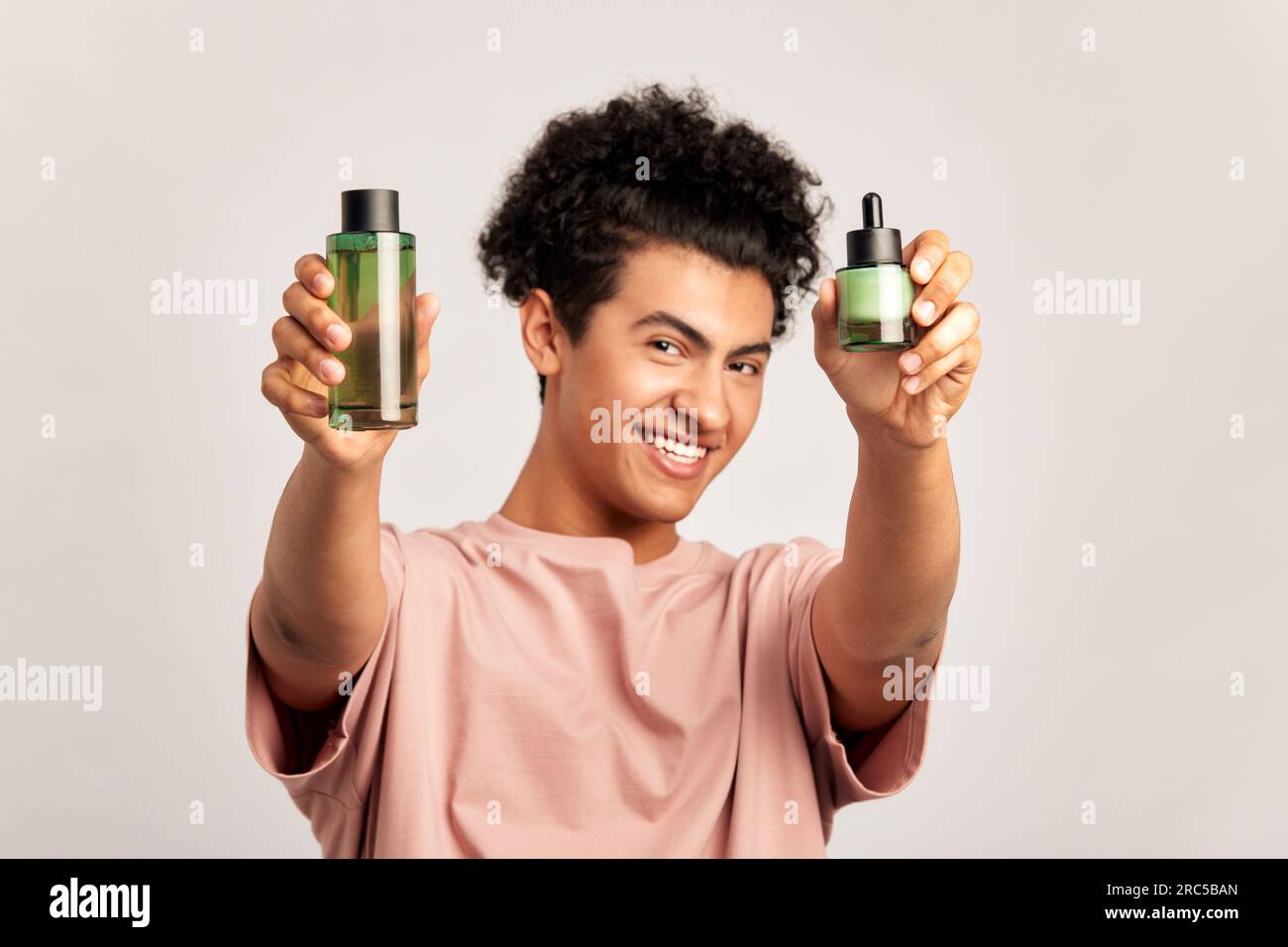 Portrait of young handsome smiling guy with bottles of moisturizing ...