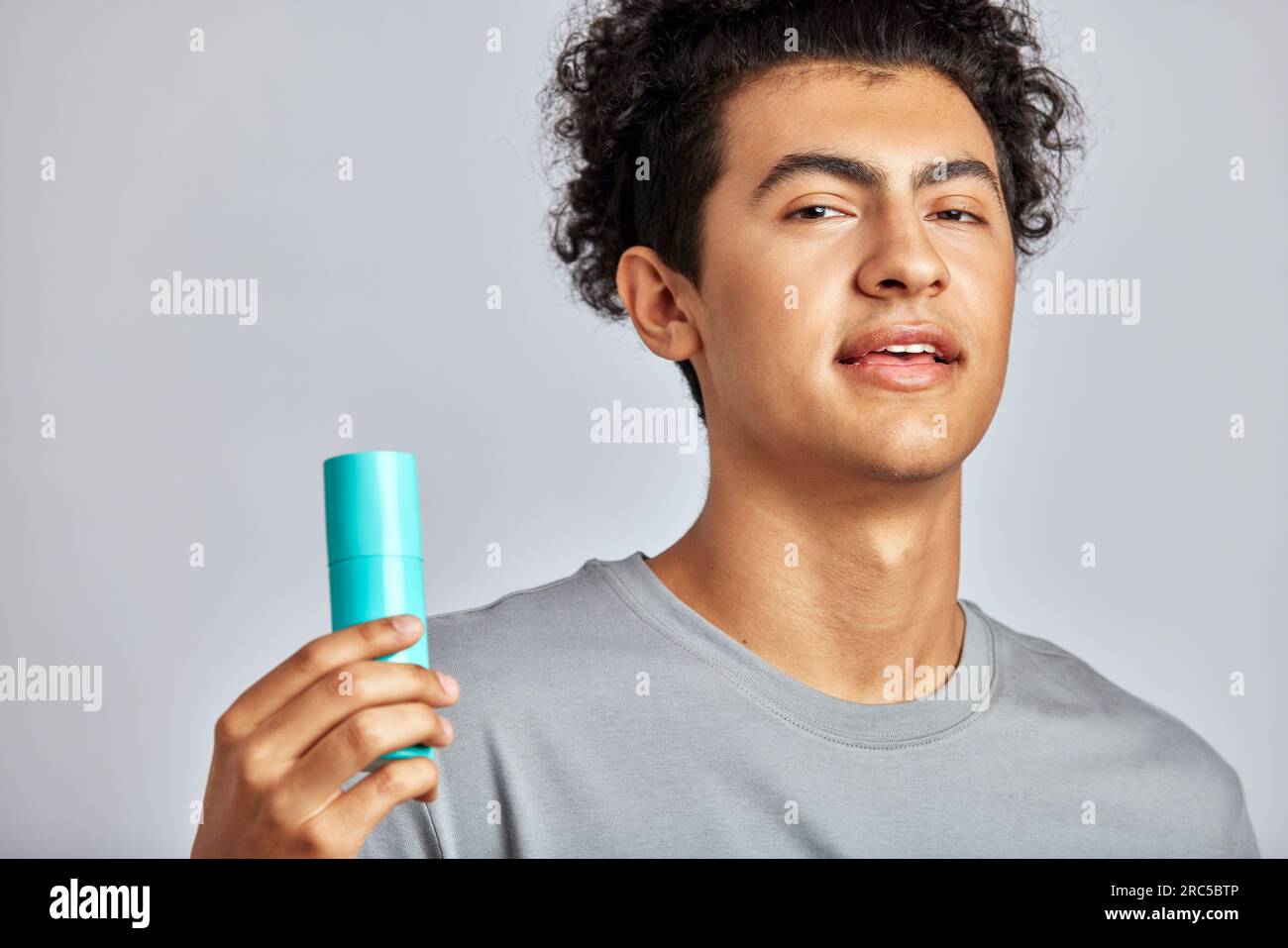 Studio portrait of a young handsome smiling guy with beauty product in ...
