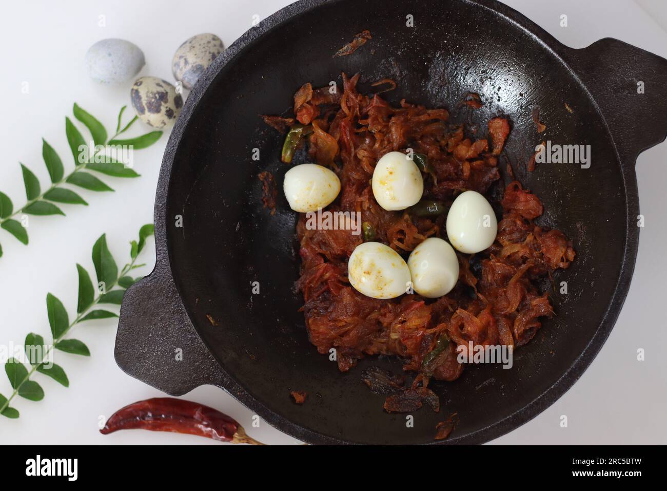 Quail egg roast cooked kerala style served in cast iron pan. It is made ...