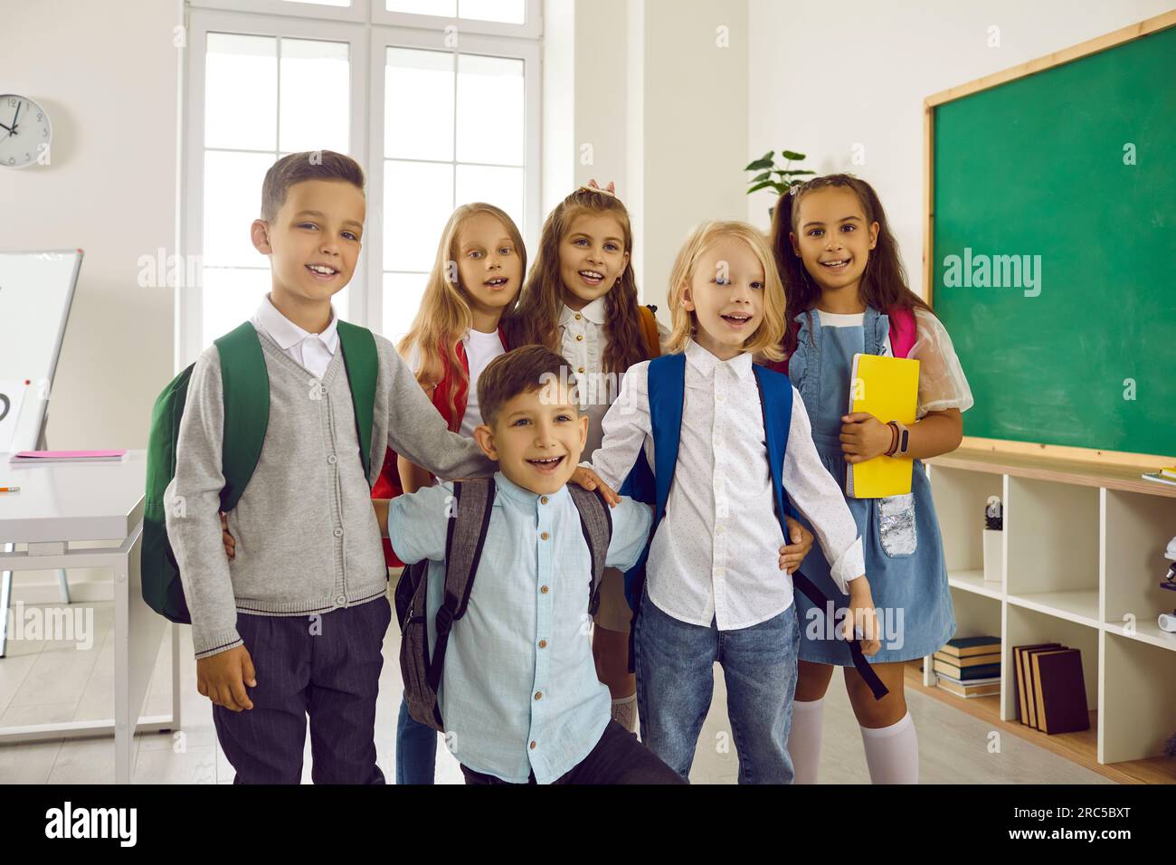 Group portrait of cheerful friends standing in the classroom on the ...