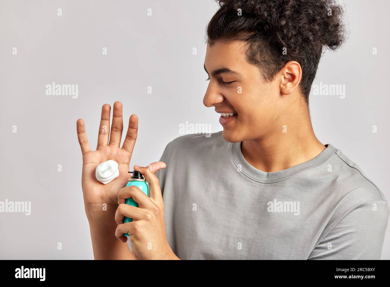 Happy young smiling guy putting facial wash on his fingers, preparing ...