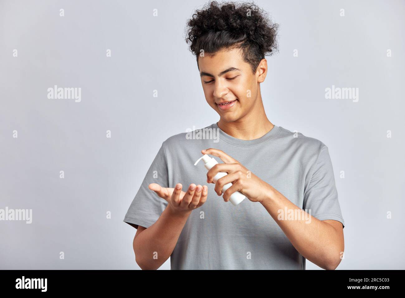Happy young smiling guy putting facial wash on his fingers, preparing ...