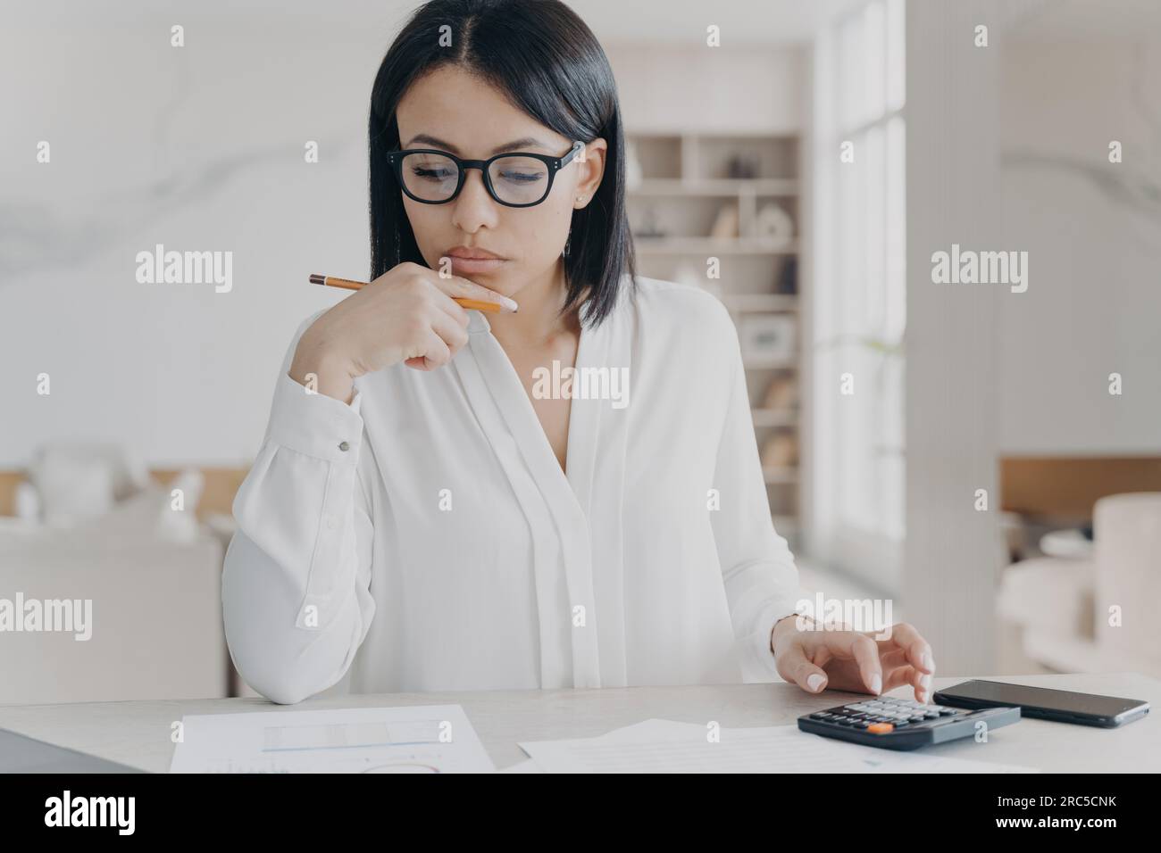 Focused businesswoman analyzes budget, calculates profit with ...