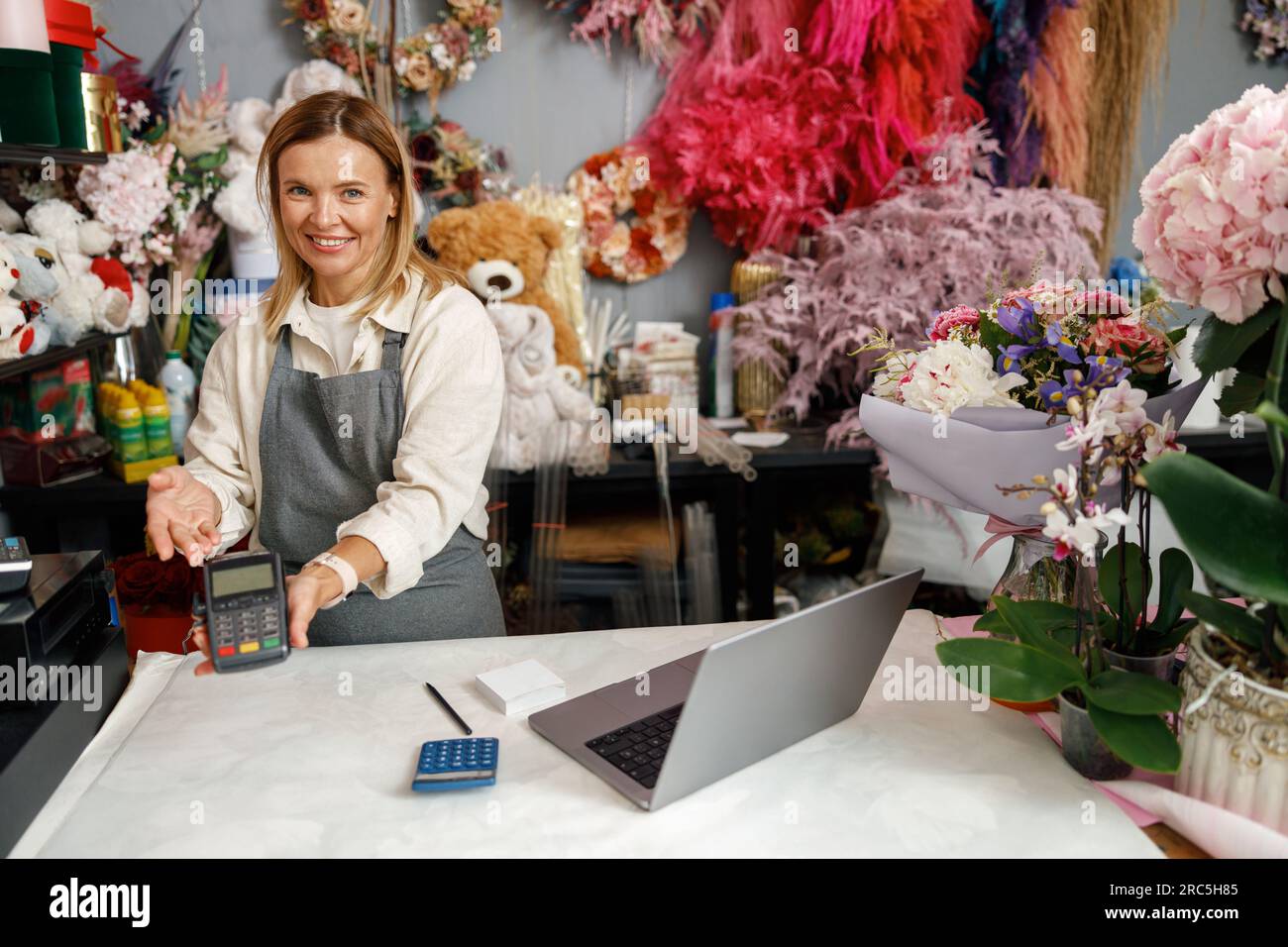 Florist holding POS terminal in floral shop and looking at camera ...