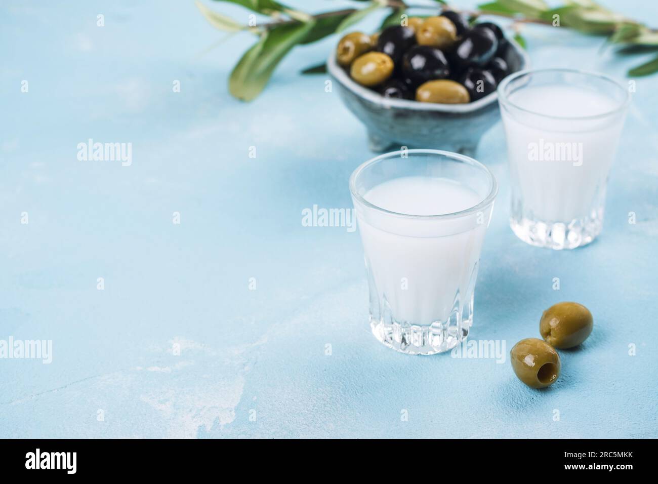 Traditional greek vodka ouzo and marinated olives on blue slate ...