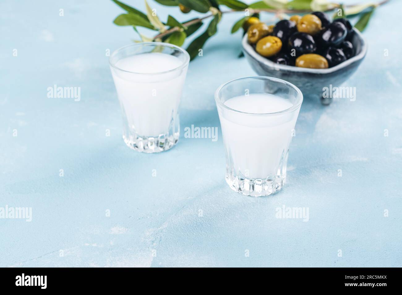 Traditional greek vodka ouzo and marinated olives on blue slate ...