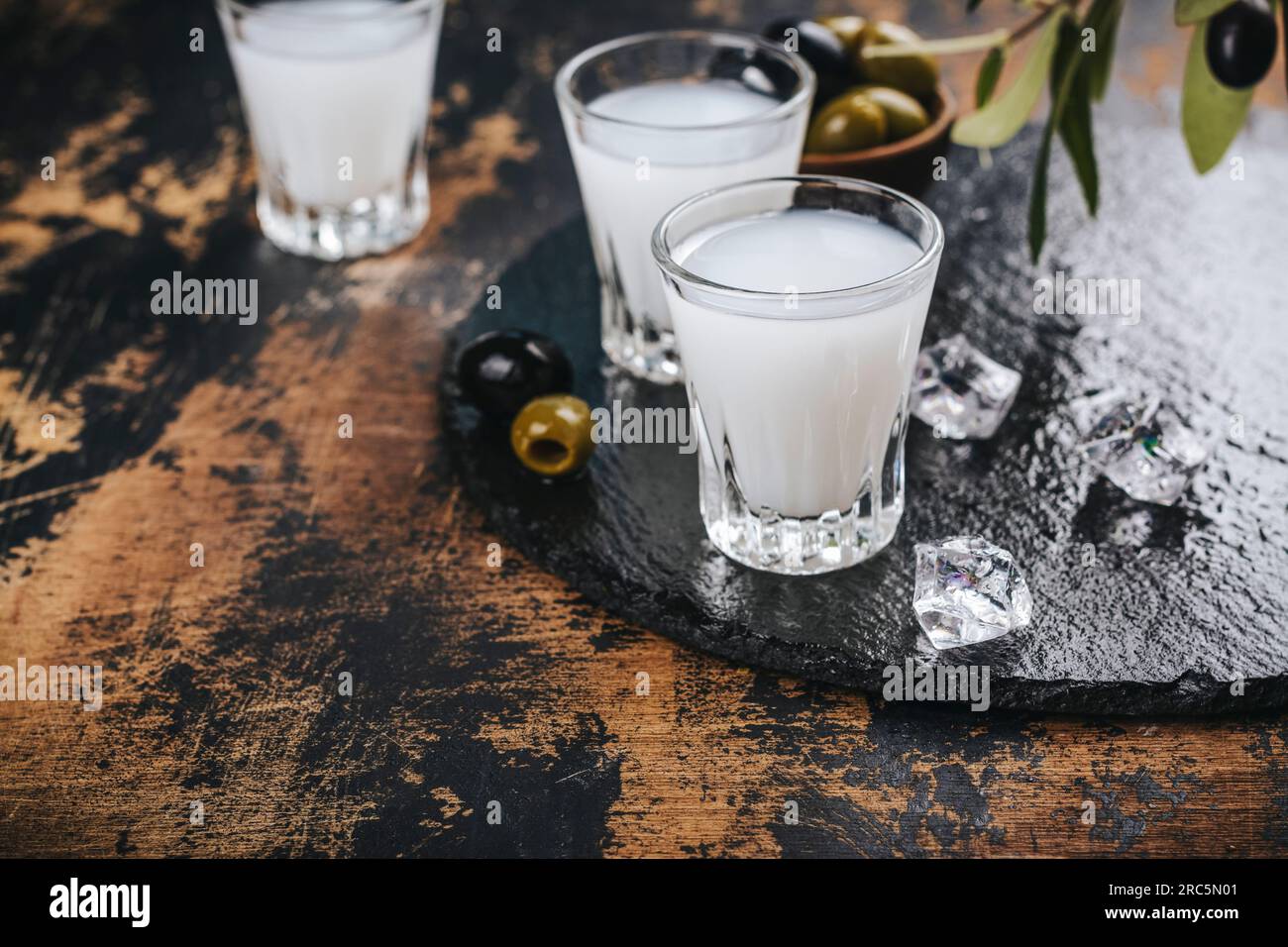 Traditional greek vodka ouzo and marinated olives on rustic wooden ...