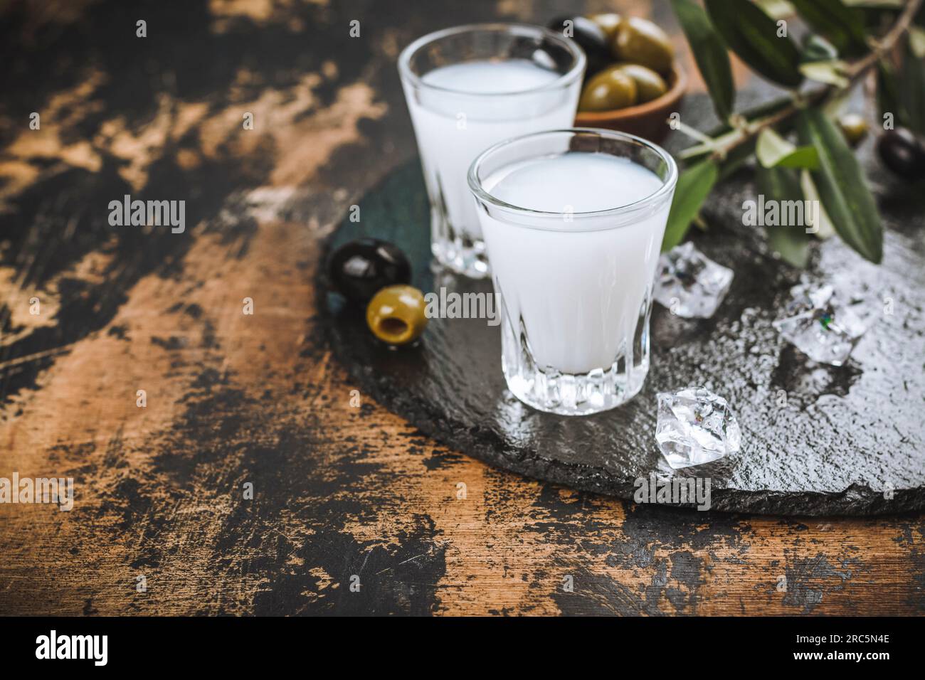 Traditional greek vodka ouzo and marinated olives on rustic wooden ...
