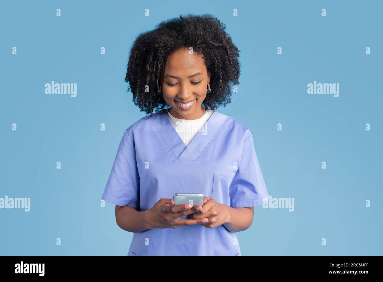 Positive young black lady doctor nurse in blue uniform typing on ...