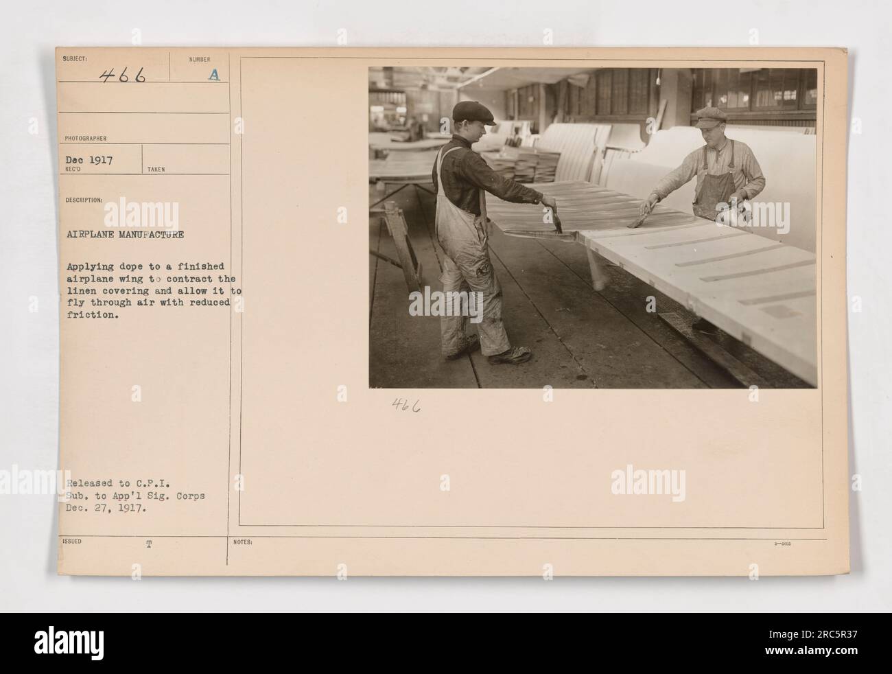 Workers applying "dope" to a finished airplane wing to contract the ...