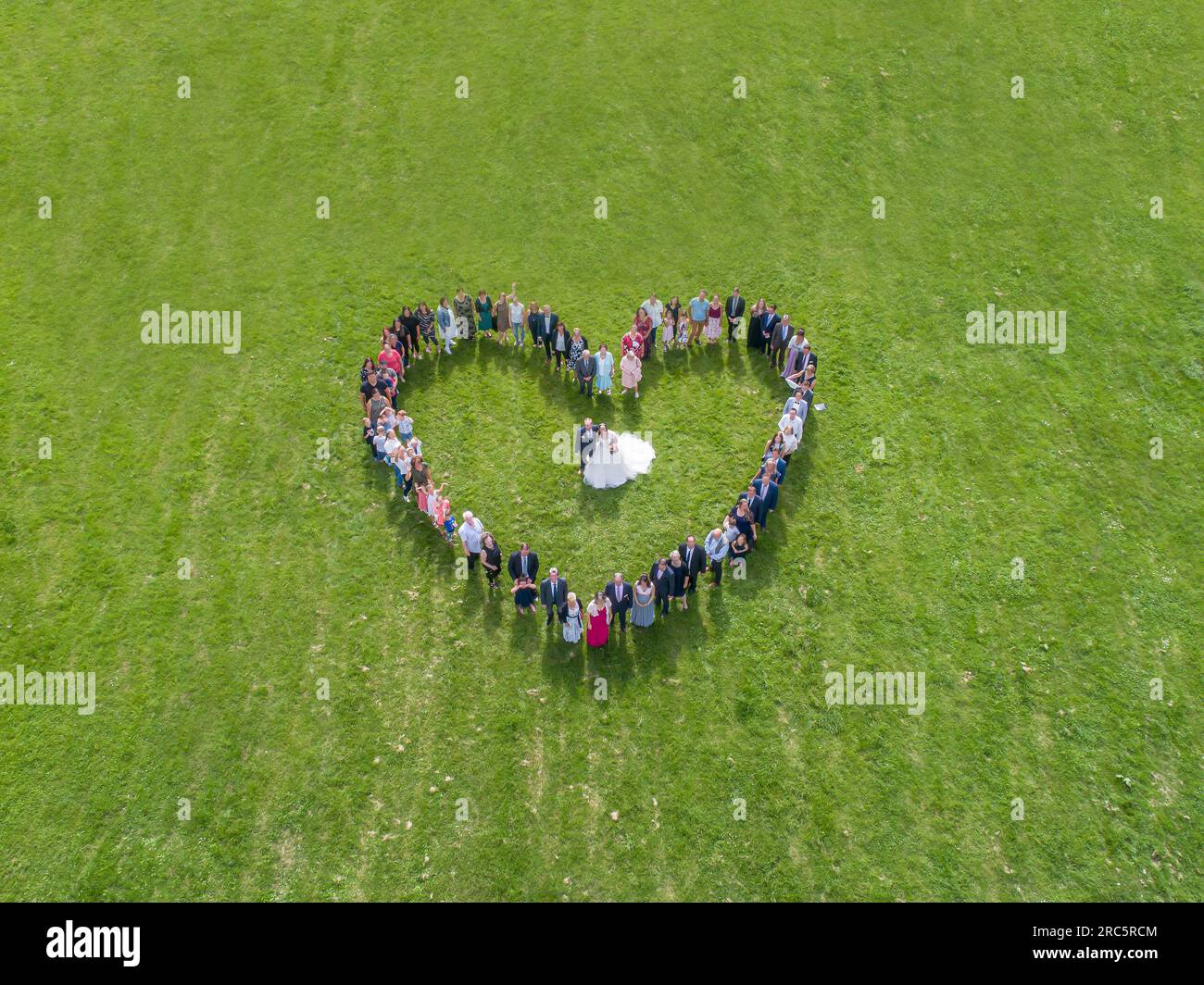 Wedding guests lined up in the shape of heart with bride and groom ...