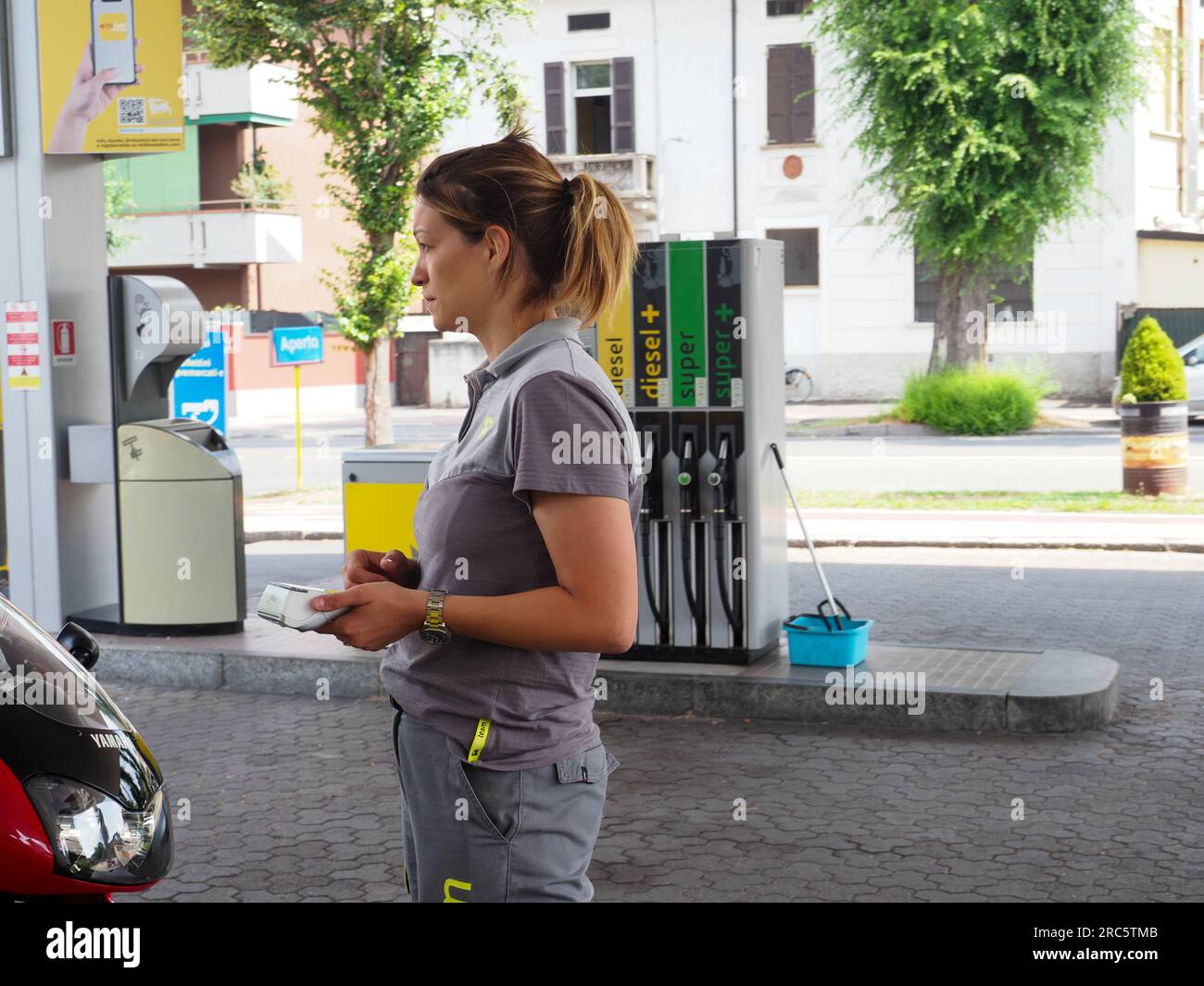 Cremona, Italy - July 3 2023 gas station attendant woman taking payments with credit card from ...