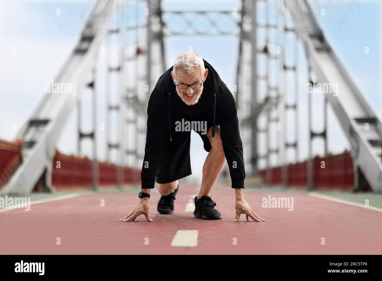 Elderly man runner standing in starting running position outdoor Stock ...