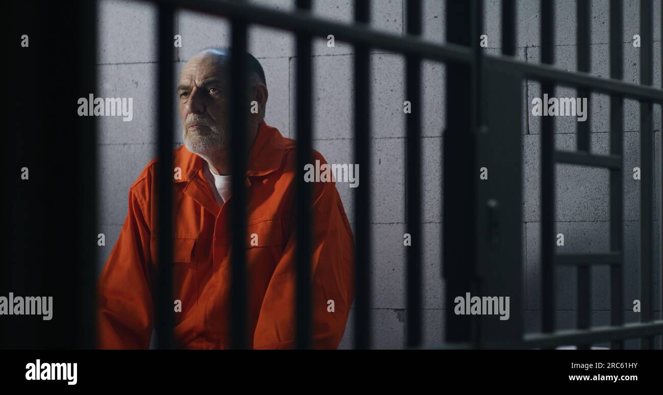 Elderly Criminal In Orange Uniform Sits On Prison Bed And Thinks About