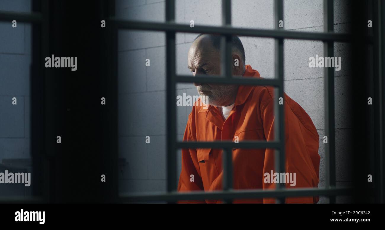 Elderly criminal in orange uniform sits on prison bed and thinks about ...