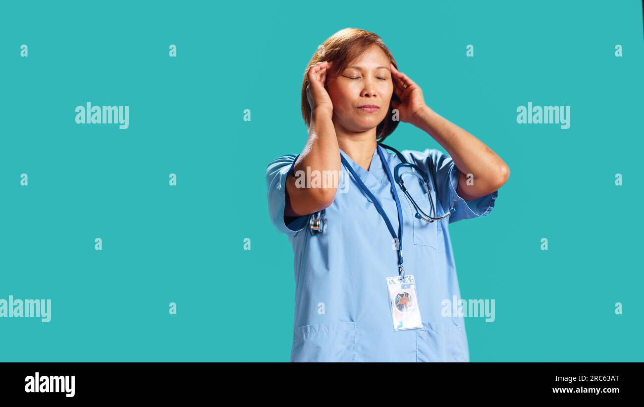 Fatigued nurse suffering from migraine pain after tiresome day at work ...