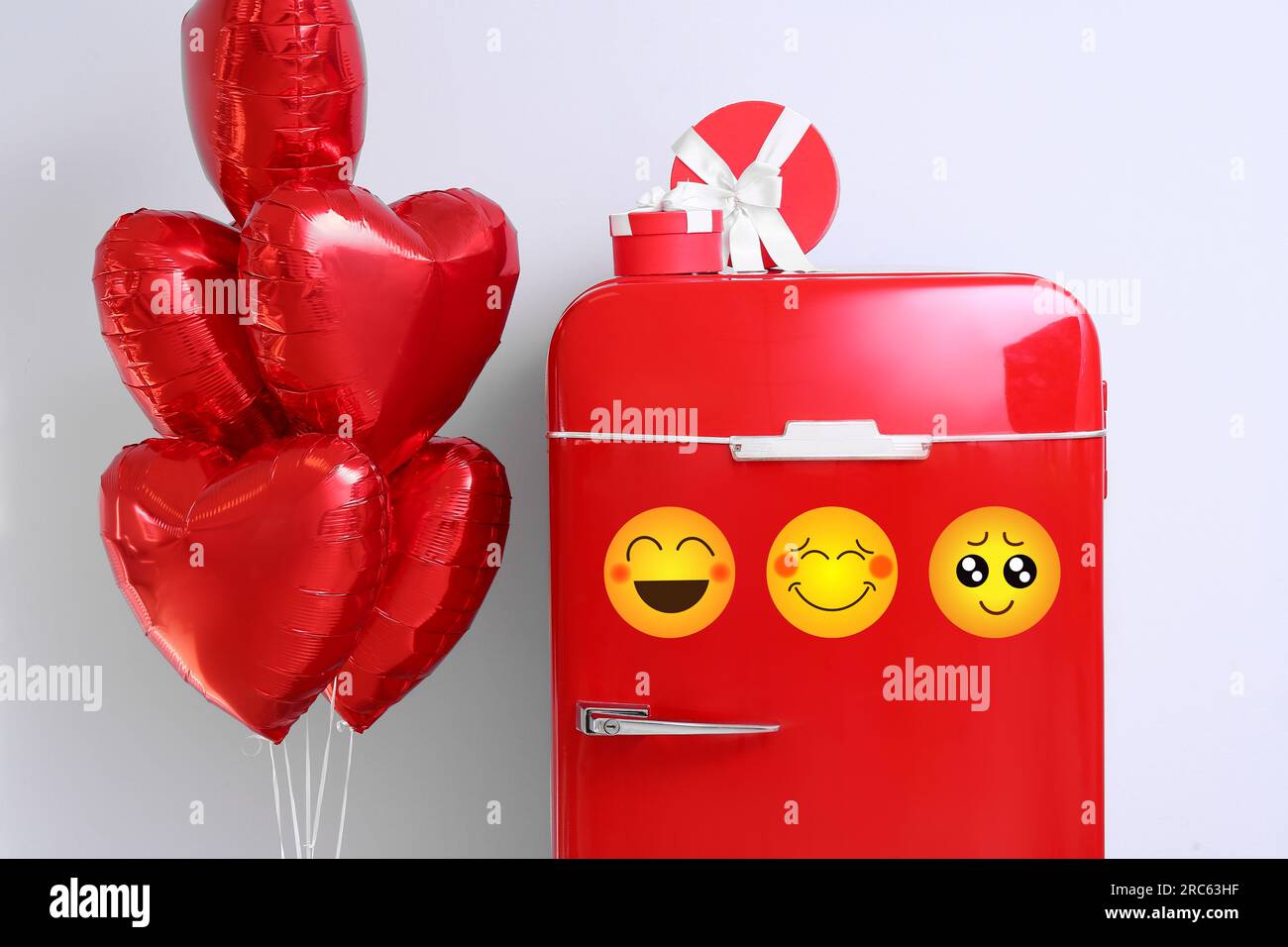 Gifts on red refrigerator with drawn cute faces and heart shaped air ...