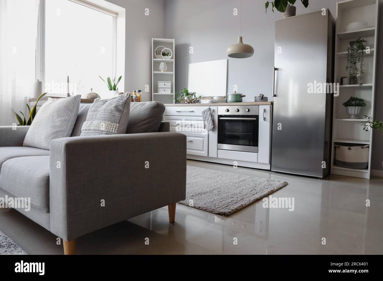 Interior of light kitchen with stylish fridge, counters, sofa and ...