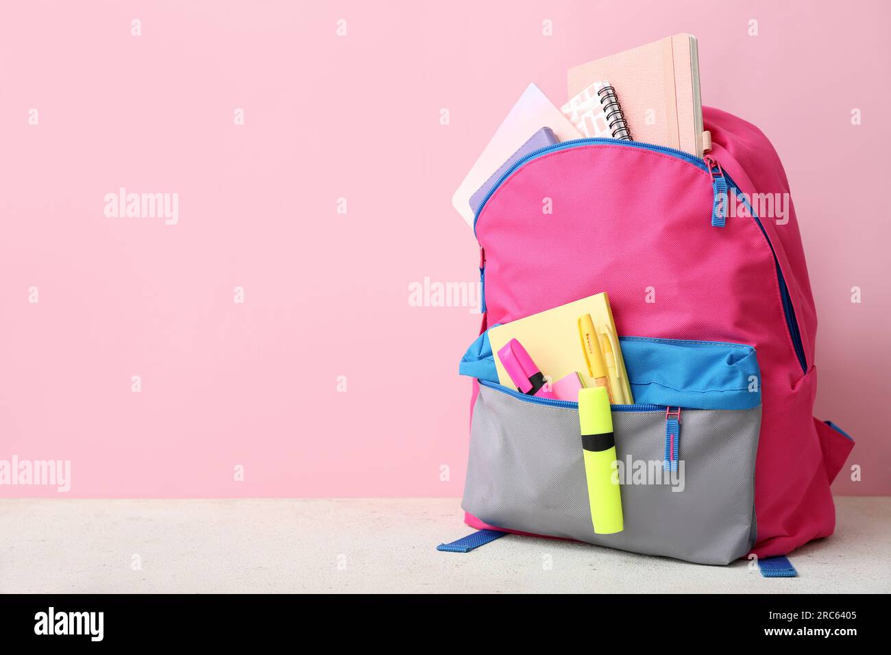 Pink school backpack with notebooks, pens and markers on white table ...