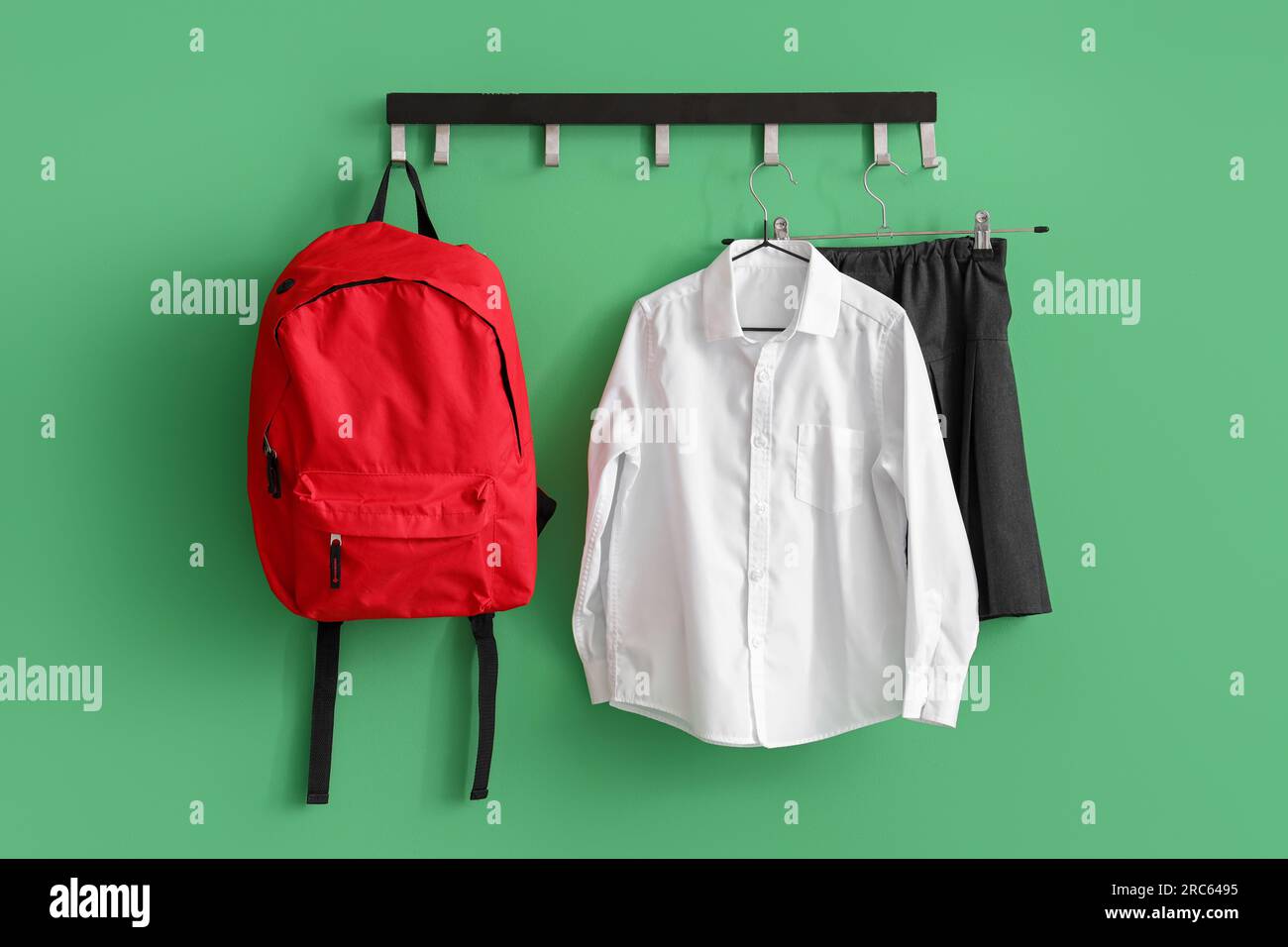 Stylish school uniform and backpack hanging on rack near green wall in ...