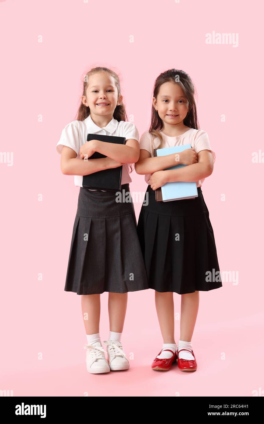 Little schoolgirls with books on pink background Stock Photo - Alamy
