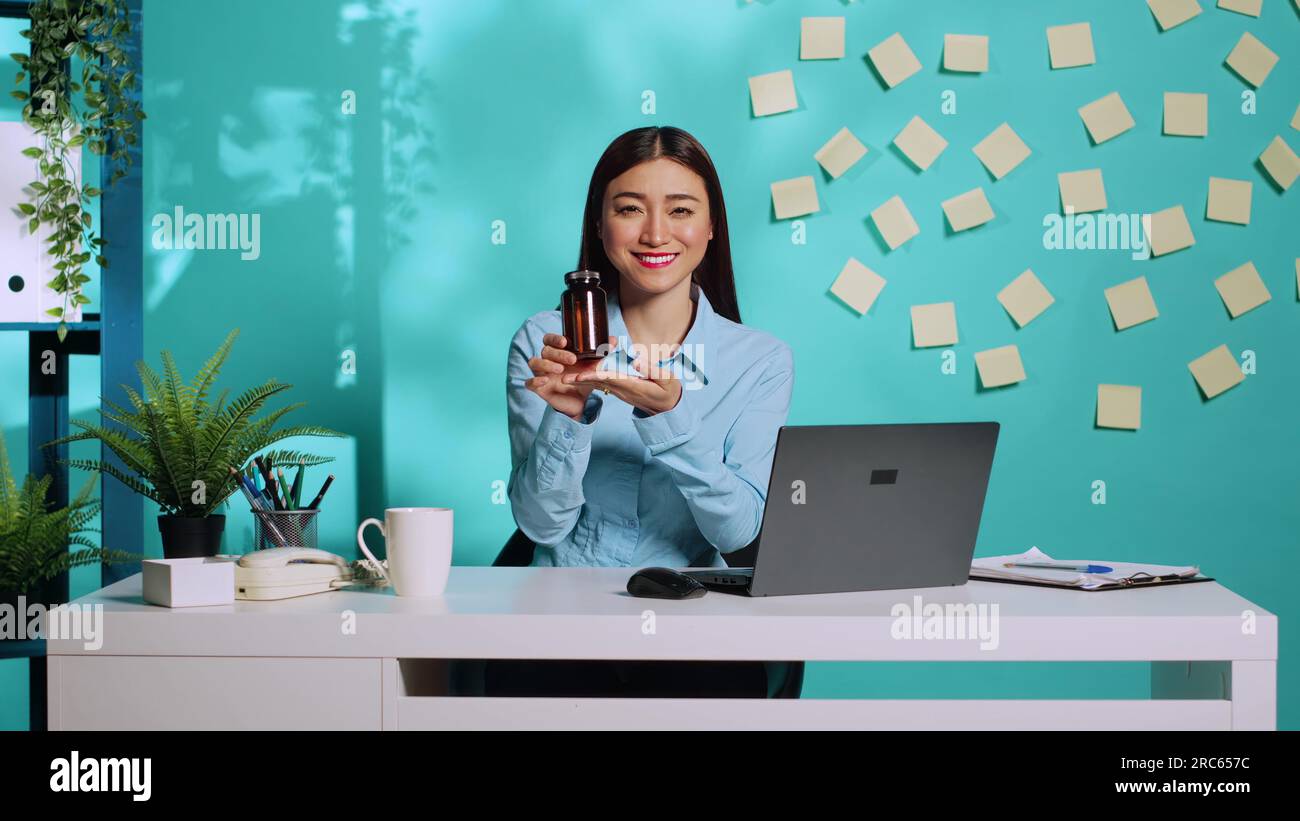 Cheerful affable asian medical saleswoman proudly presenting pill ...