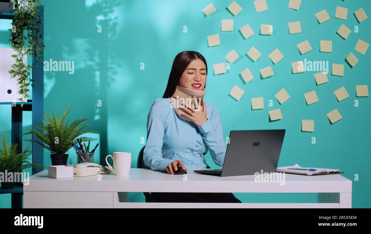 Injured woman wearing cervical collar cast struggling while working on ...