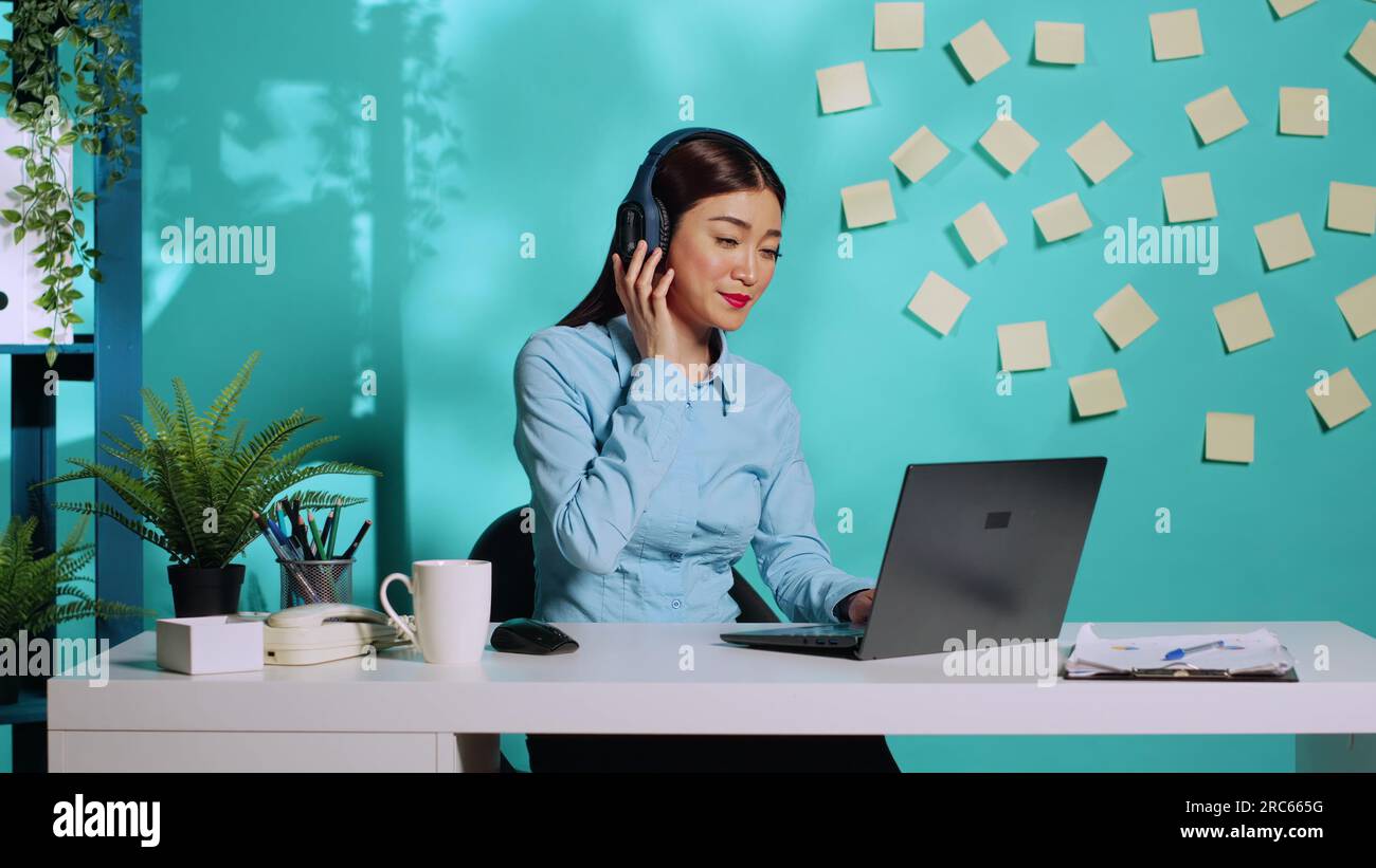 Happy asian woman enjoying music over headphones, singing and dancing ...