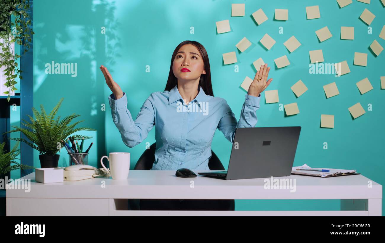 Worried employee praying looking up with hands raised toward the sky ...