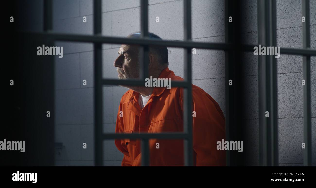 Elderly Criminal In Orange Uniform Sits On Prison Bed And Thinks About