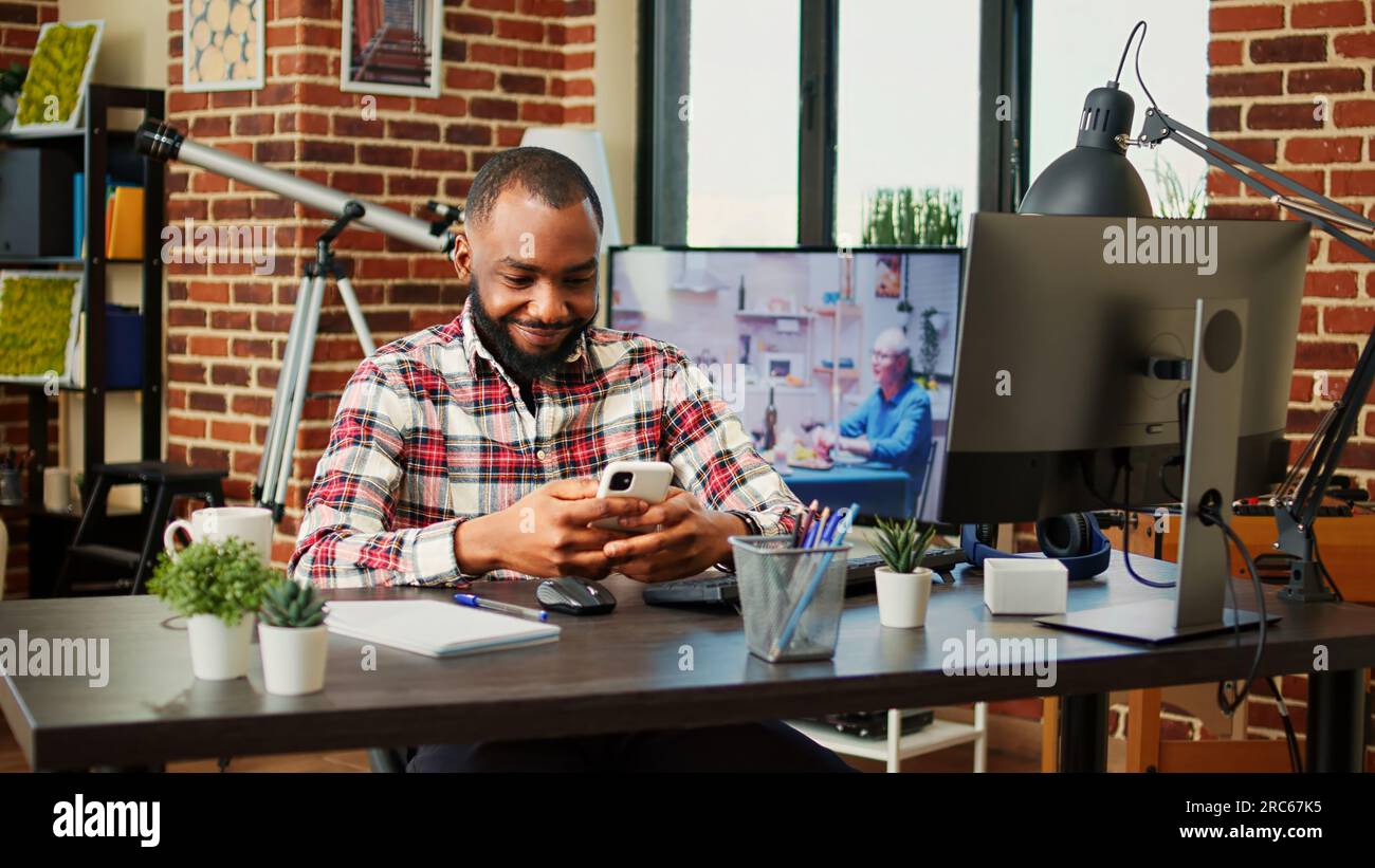 Relaxed african american man scrolling on his phone entertained by ...
