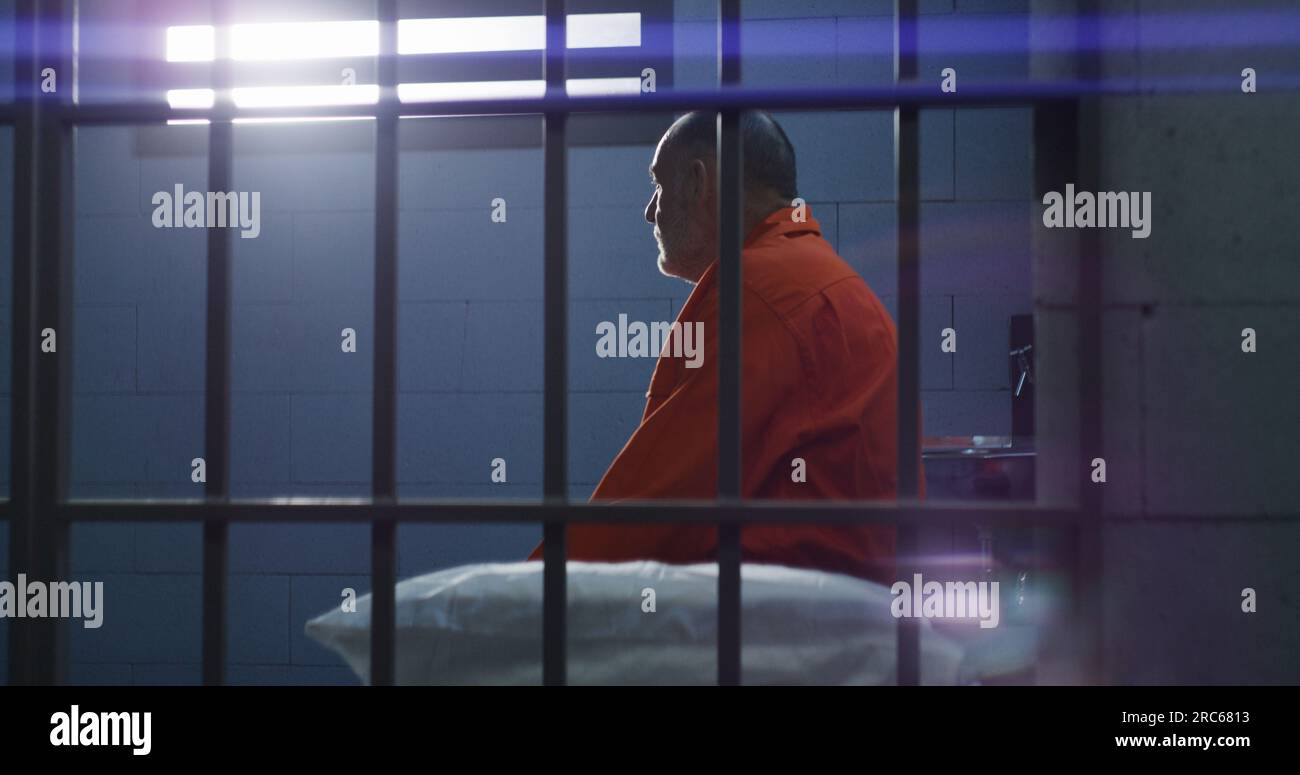 Number of jail cell on the wall. Elderly criminal in orange uniform ...