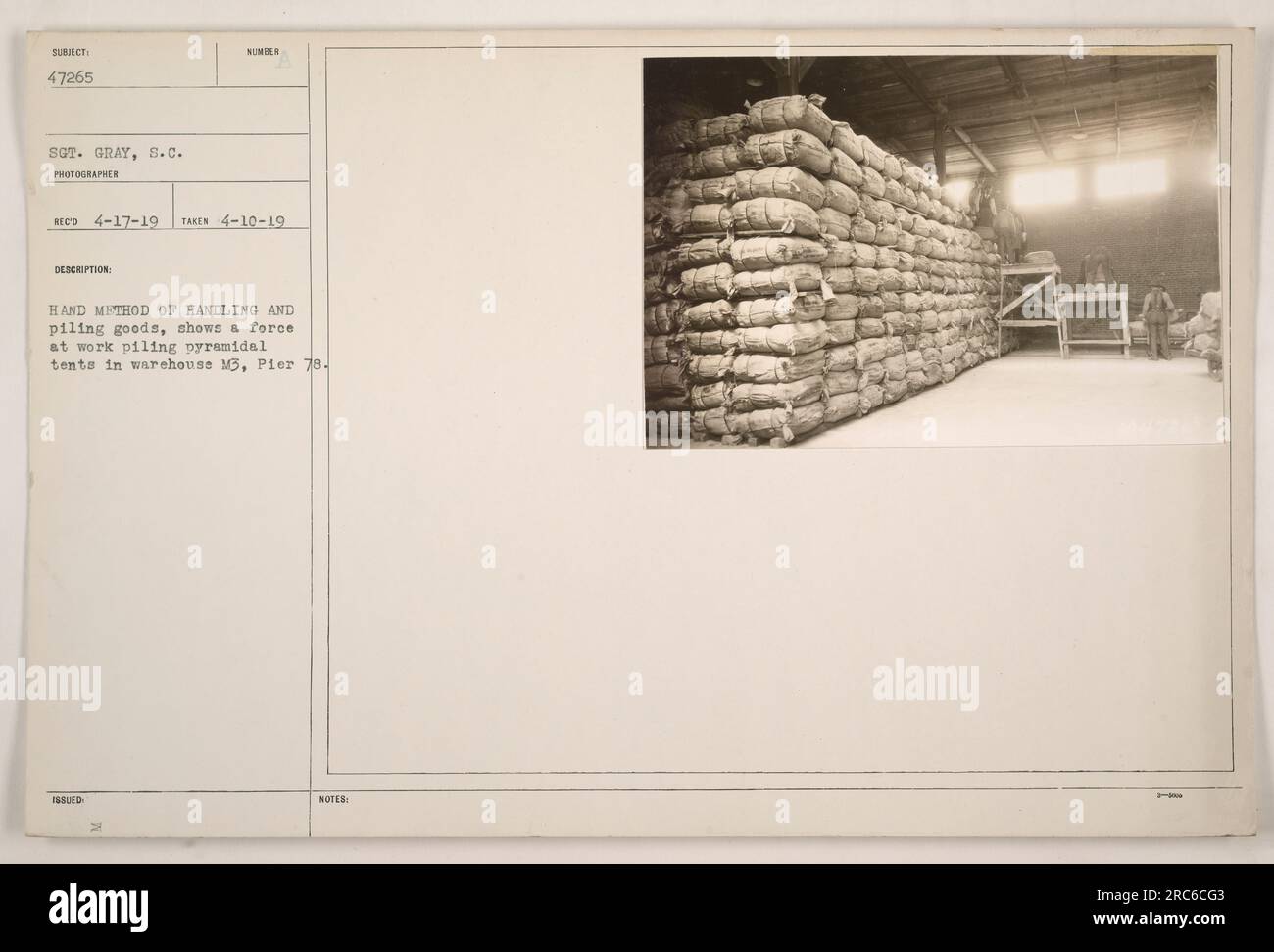 Soldiers actively working to stack pyramidal tents inside warehouse M3 ...