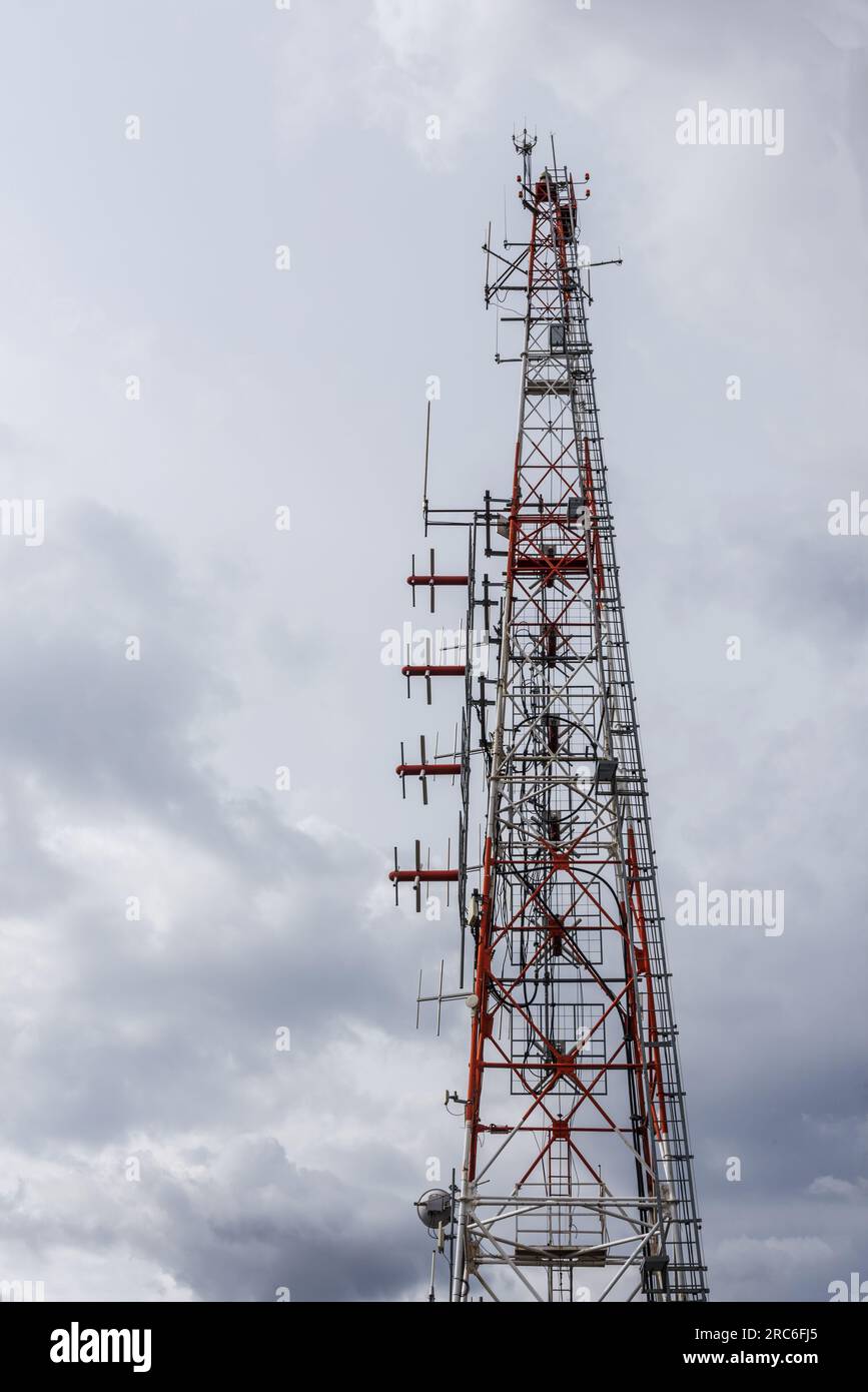 A tall telecommunication tower with antennas and a service staircase on a day with a lot of ...