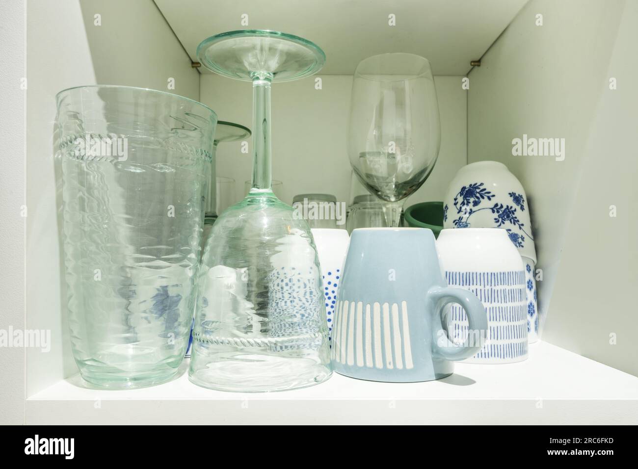 Disparate piece glassware stored in a white cupboard Stock Photo - Alamy