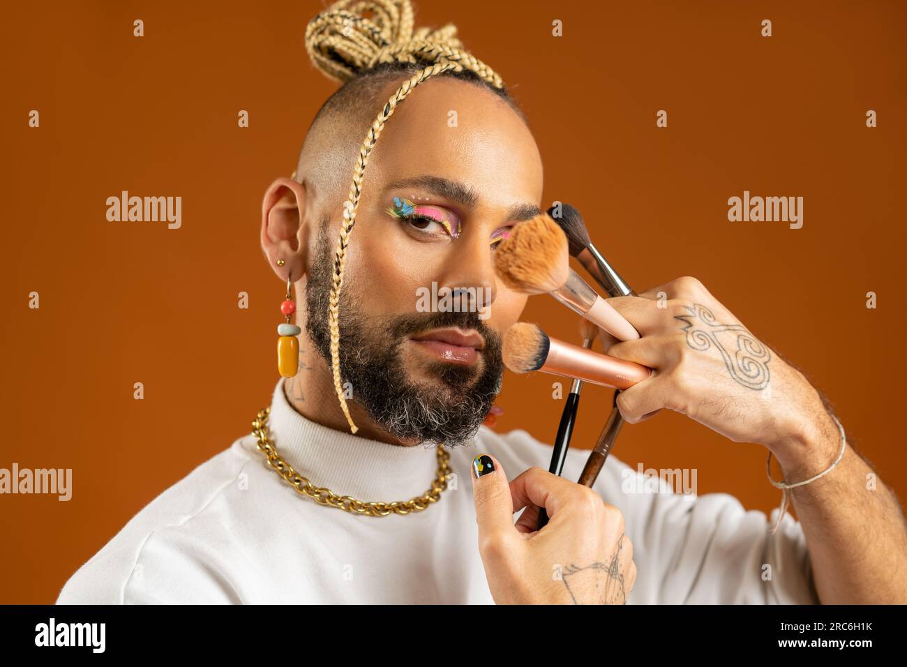 African american gay with bright make up holding makeup brush. Handsome ...