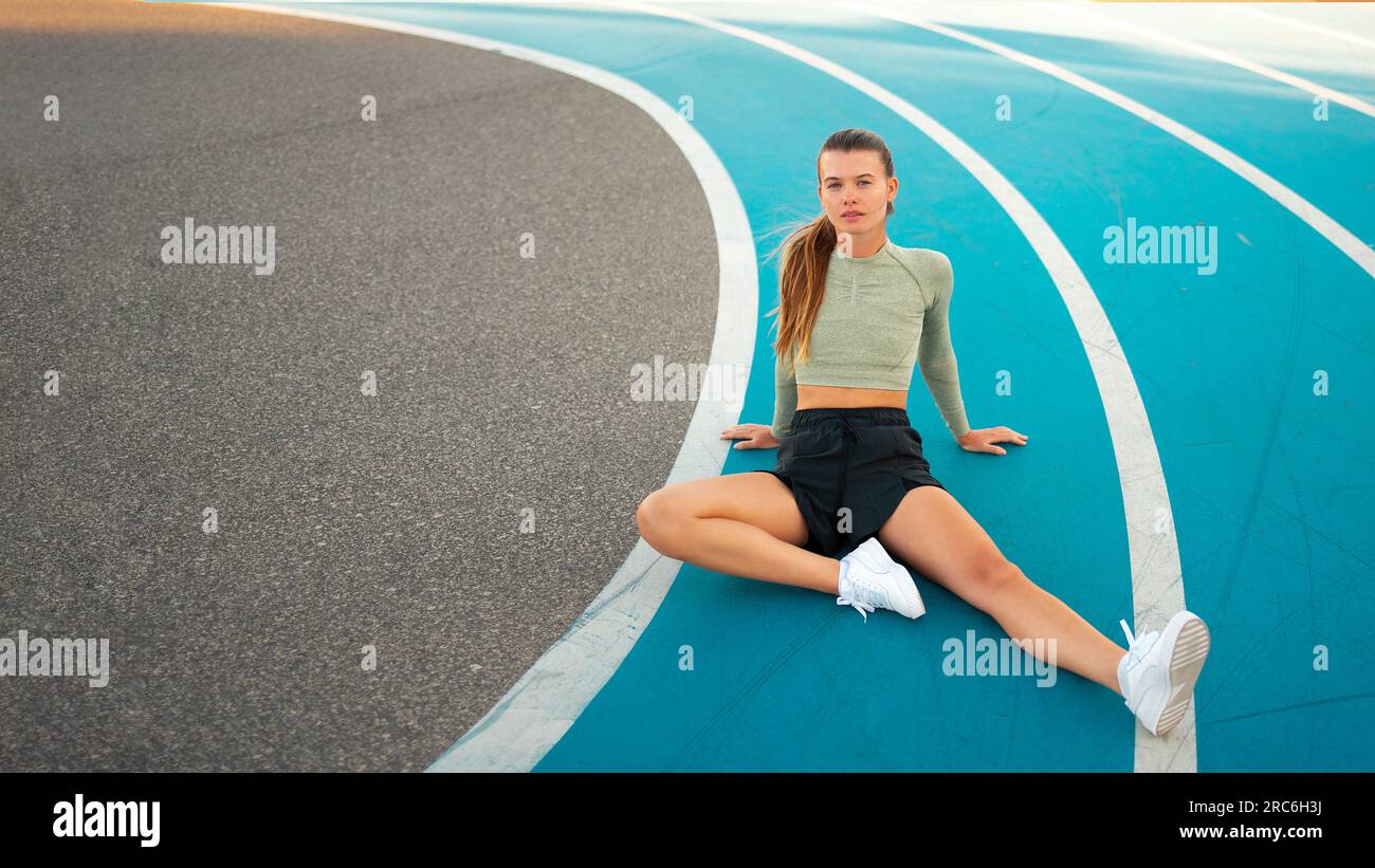 Tired happy woman runner taking rest after run sitting on the running ...