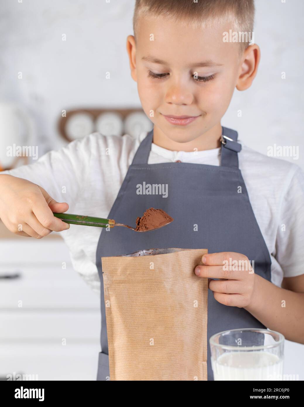 Cute boy cooks hot chocolate from cocoa powder and milk. Hot cacao ...