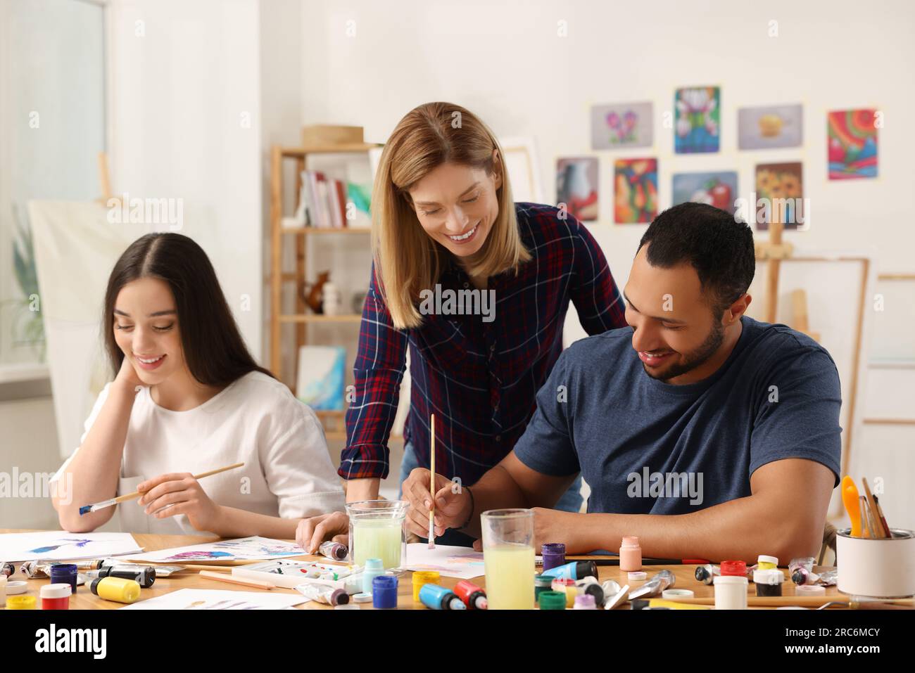 Artist teaching her students to paint at table in studio. Creative ...