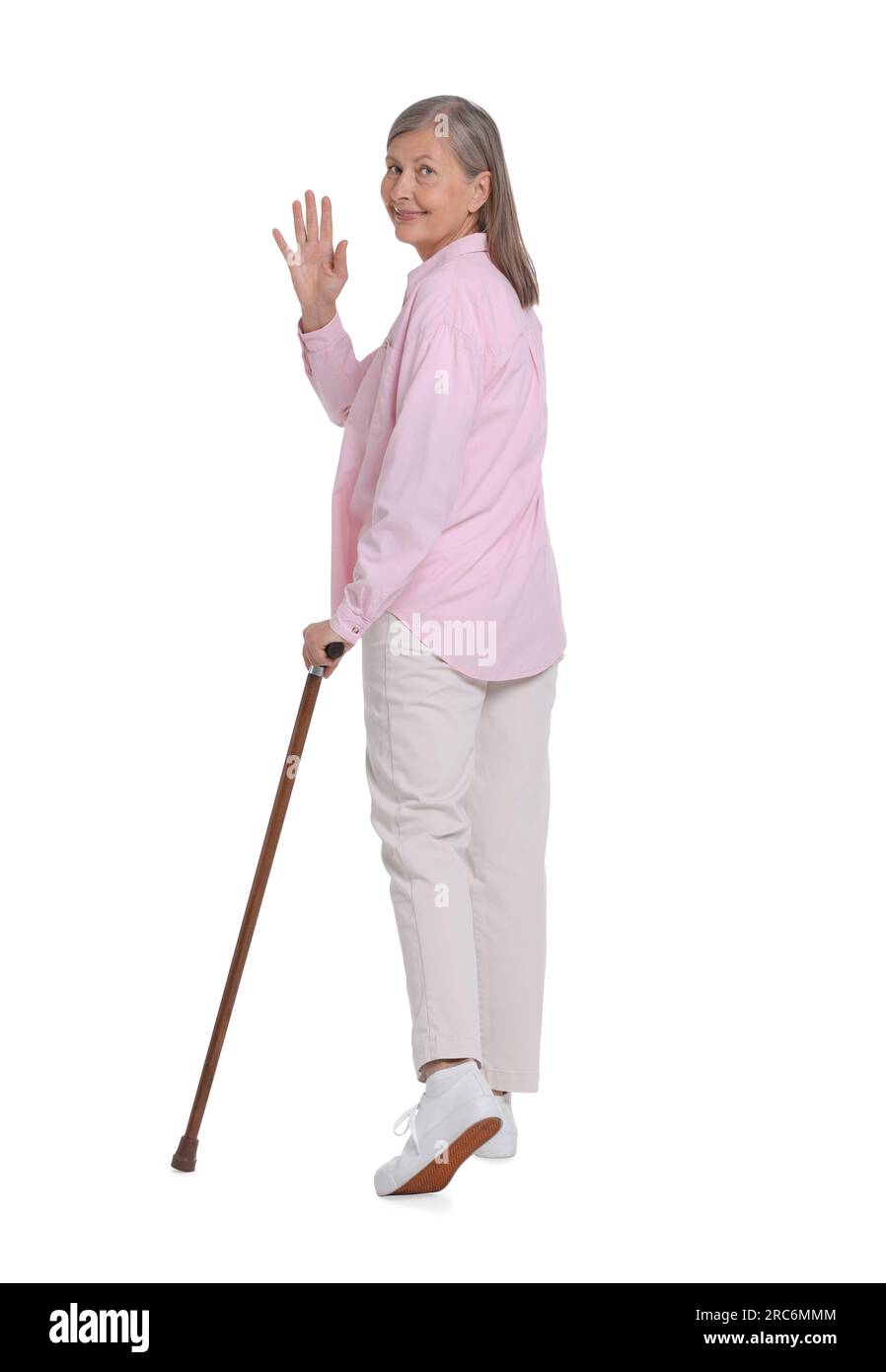 Senior woman with walking cane waving on white background Stock Photo ...
