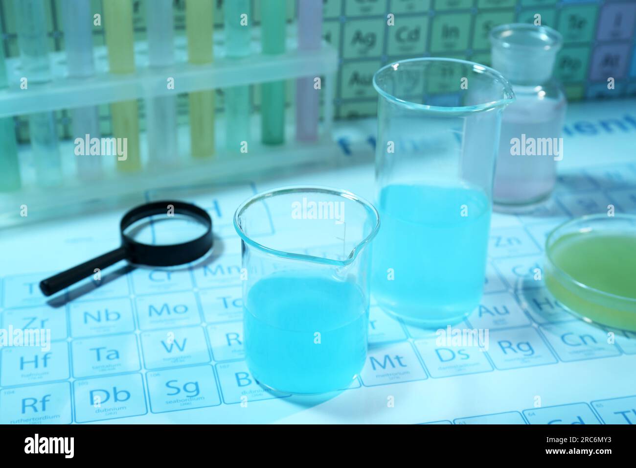 Beakers with liquid, different laboratory glassware and magnifying ...