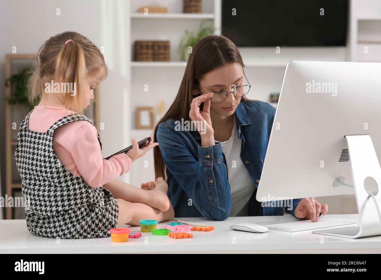 Woman working remotely at home. Tired mother using computer while her ...