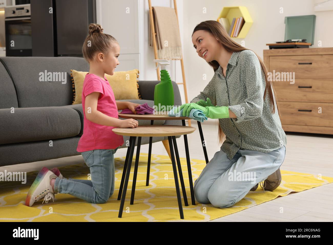 Spring cleaning. Mother and daughter tidying up living room together ...