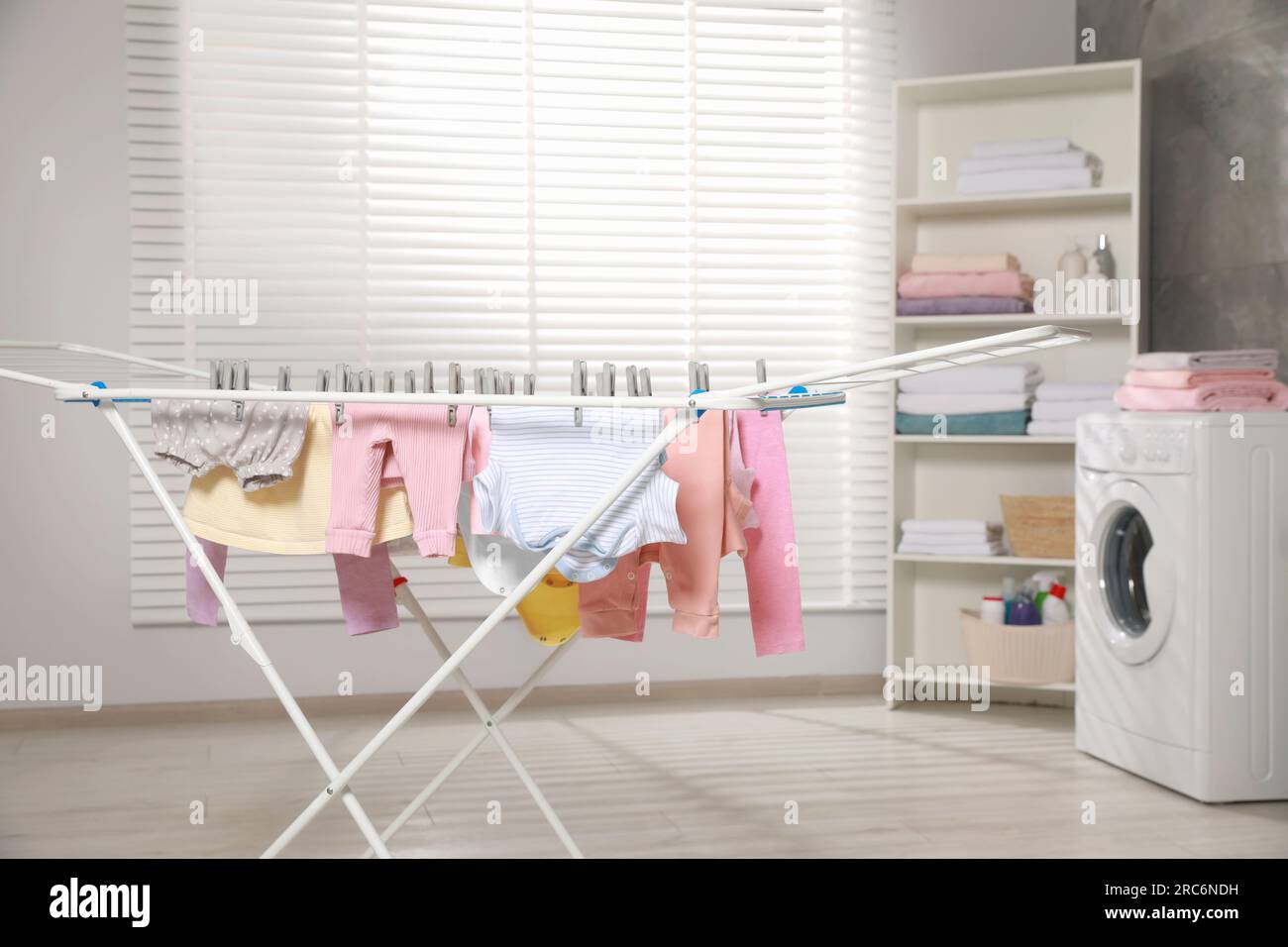 Clean laundry hanging on drying rack indoors Stock Photo - Alamy