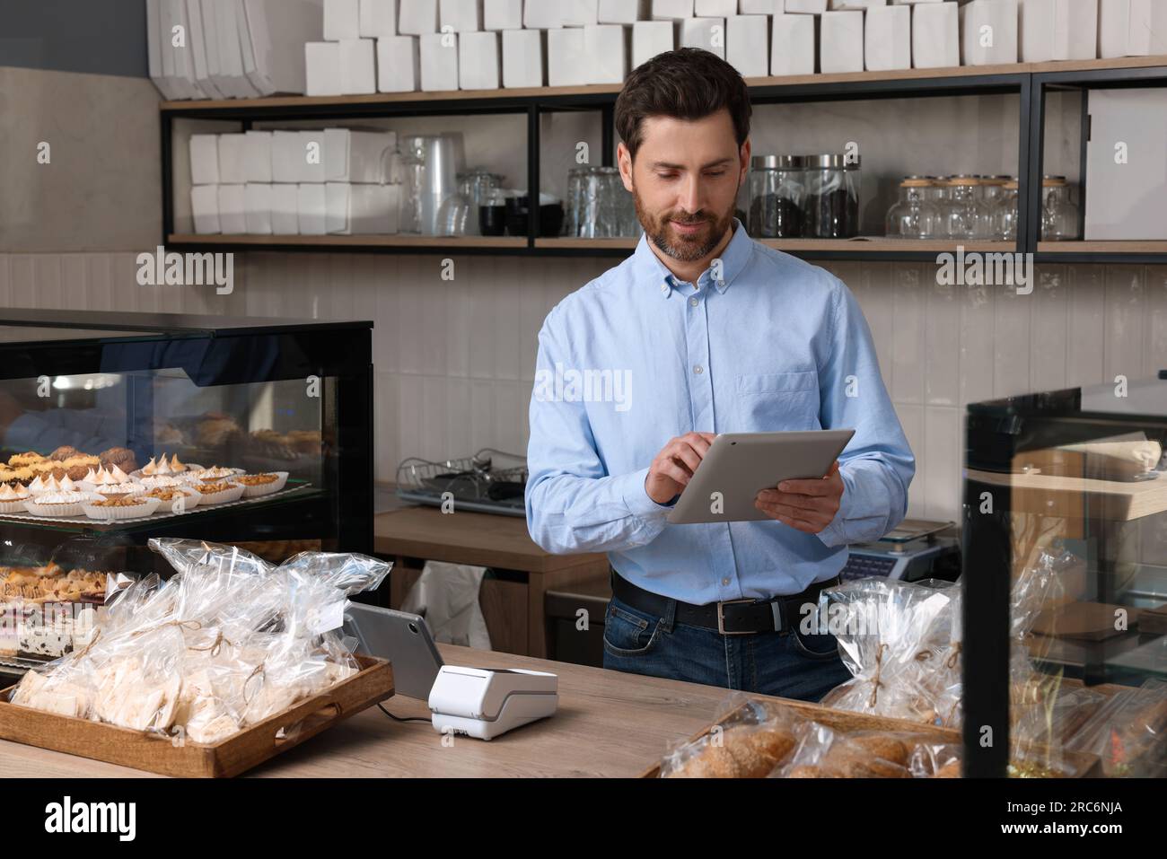 Smiling business owner with tablet at cashier desk in bakery shop Stock ...