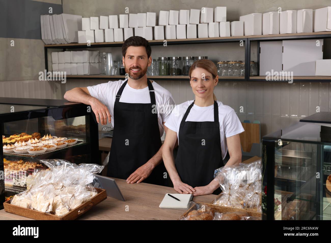 Happy sellers at cashier desk near showcase in bakery shop Stock Photo ...