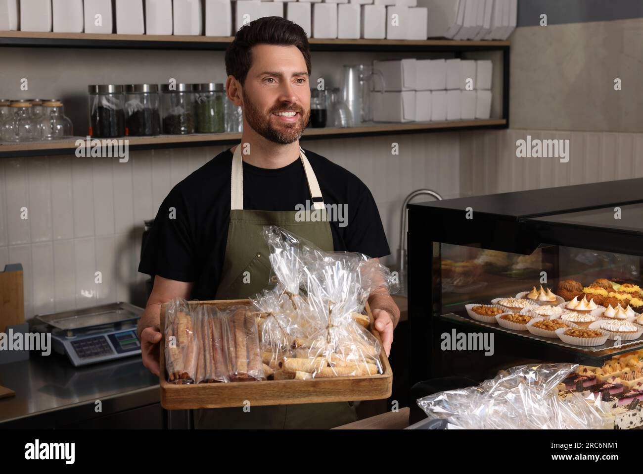 Happy seller with pastries at cashier desk in bakery shop Stock Photo ...